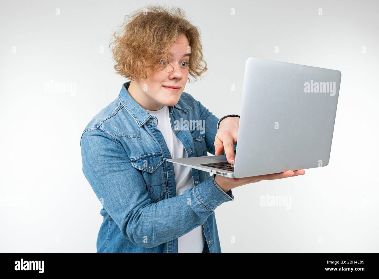 blond guy is typing on a keyboard a message on a laptop on a white ...