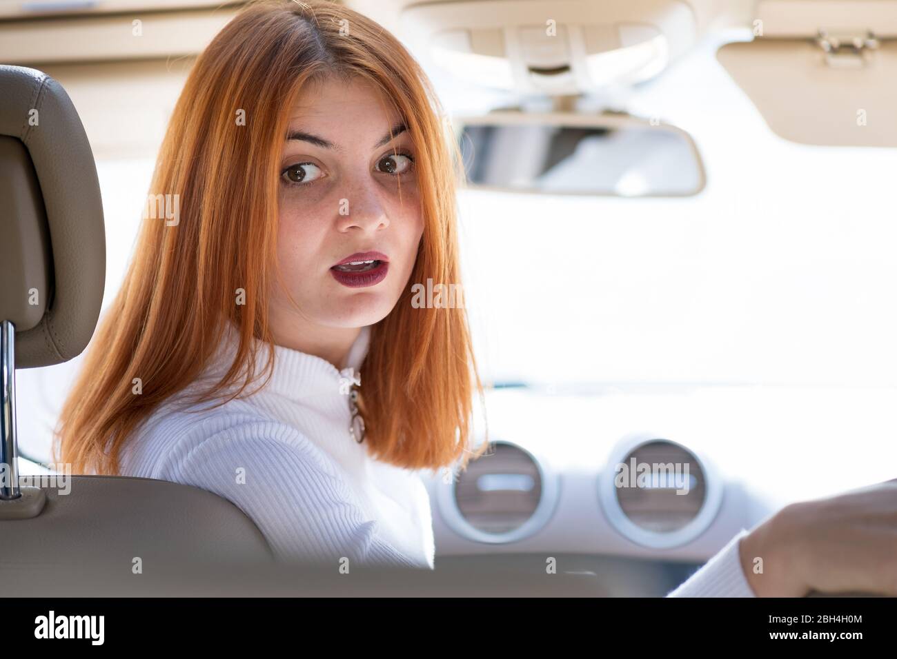 Young redhead woman driver driving a car backwards Stock Photo - Alamy