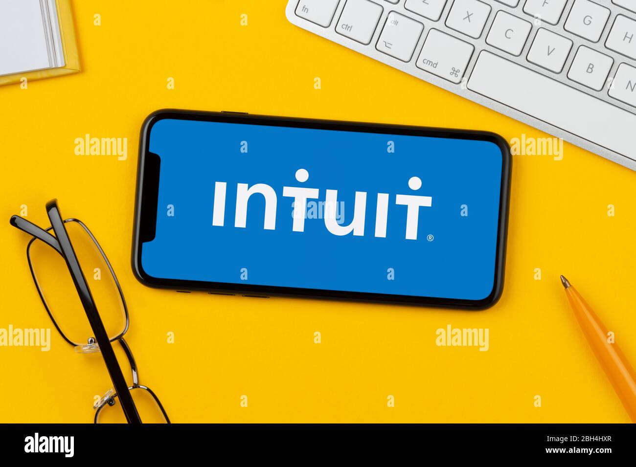 A smartphone showing the Intuit logo rests on a yellow background along ...