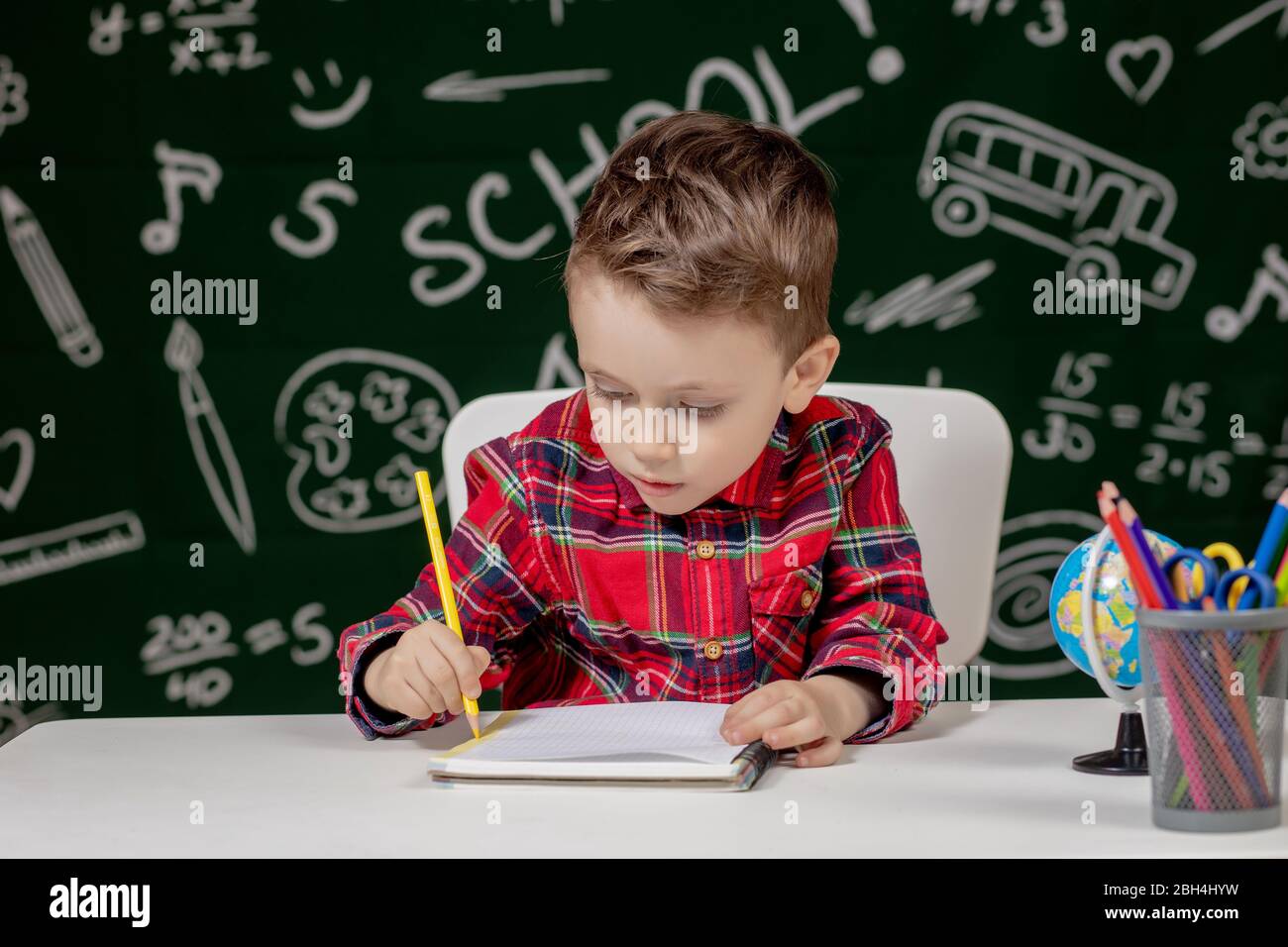 Cute child boy doing homework. Clever kid drawing at desk. Schoolboy ...