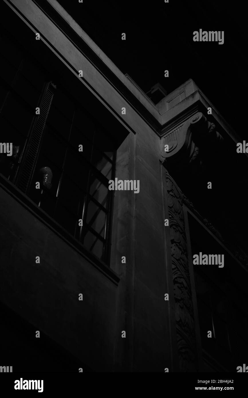 Black and white exterior of a brick building and single window at night ...