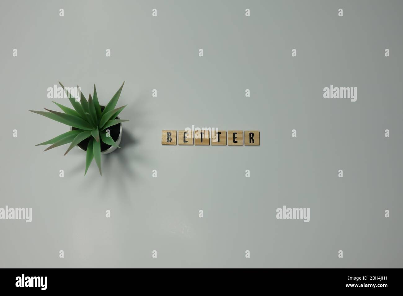 The word Better written in wooden letter tiles on a white background ...