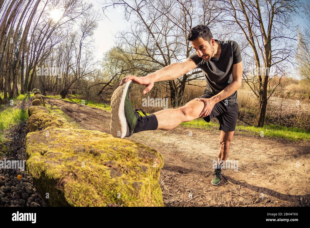 Male runner stretching outdoors on nature in misty forest full of ...