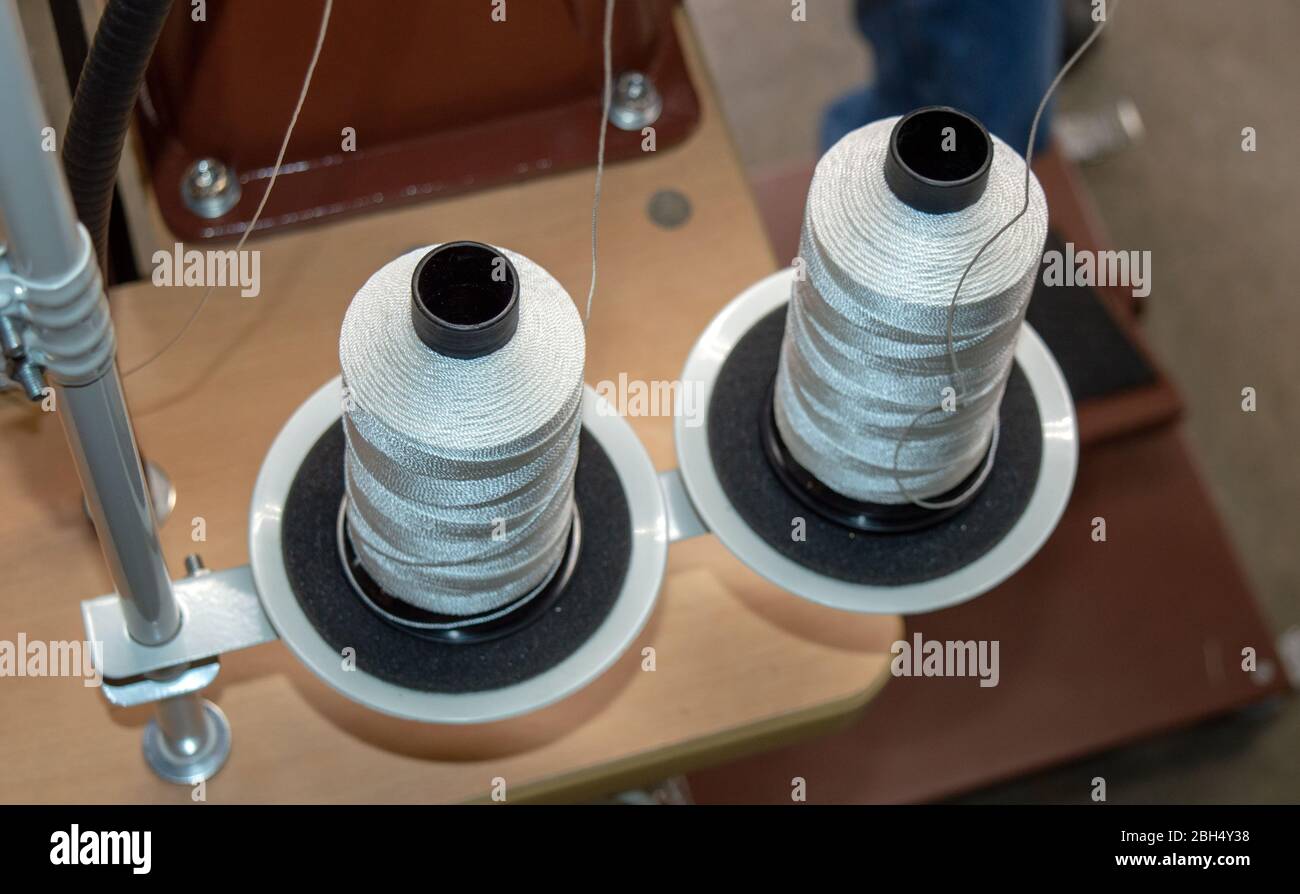 A top down view of two spools of thread on a leather sewing machine ...