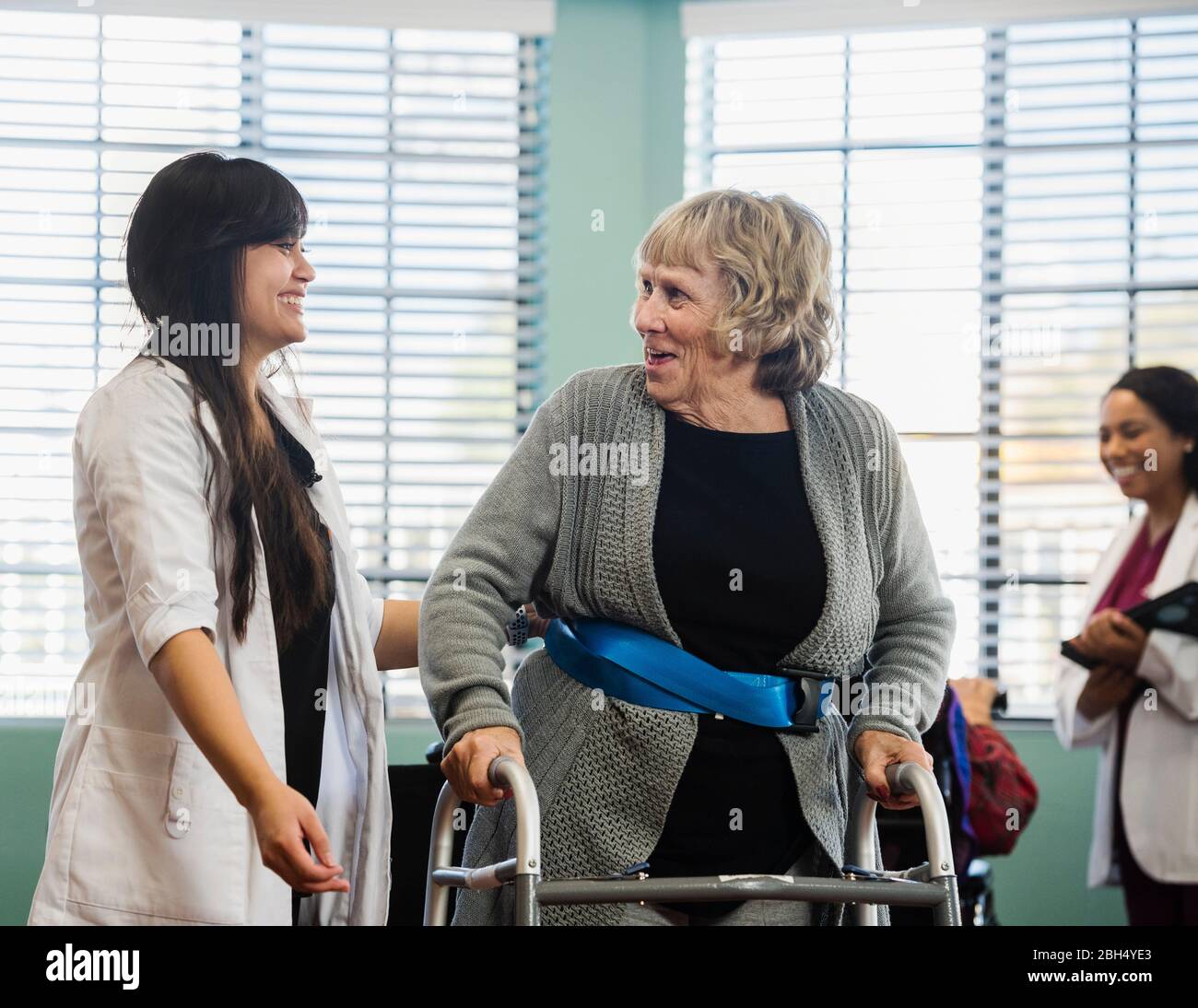 Smiling doctor helping senior woman use walking frame Stock Photo - Alamy