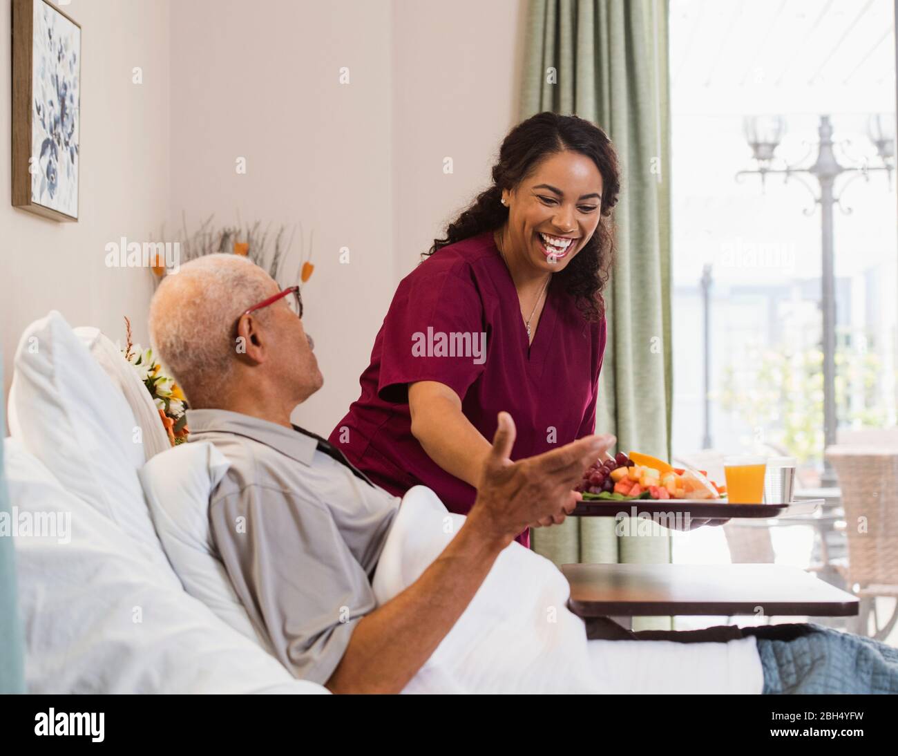 Smiling nurse hanging food to senior man in bed Stock Photo - Alamy