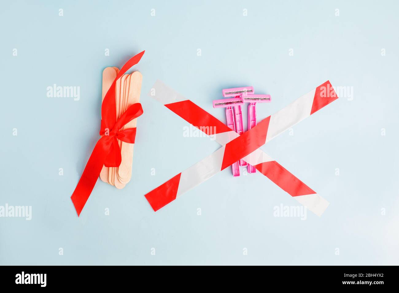 Waxing wooden stick spatula Board to a pink shaving machine on blue ...