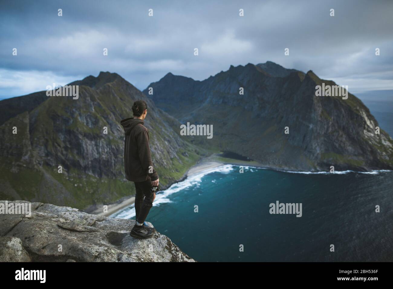 Man holding camera on cliff at Ryten mountain in Lofoten Islands ...