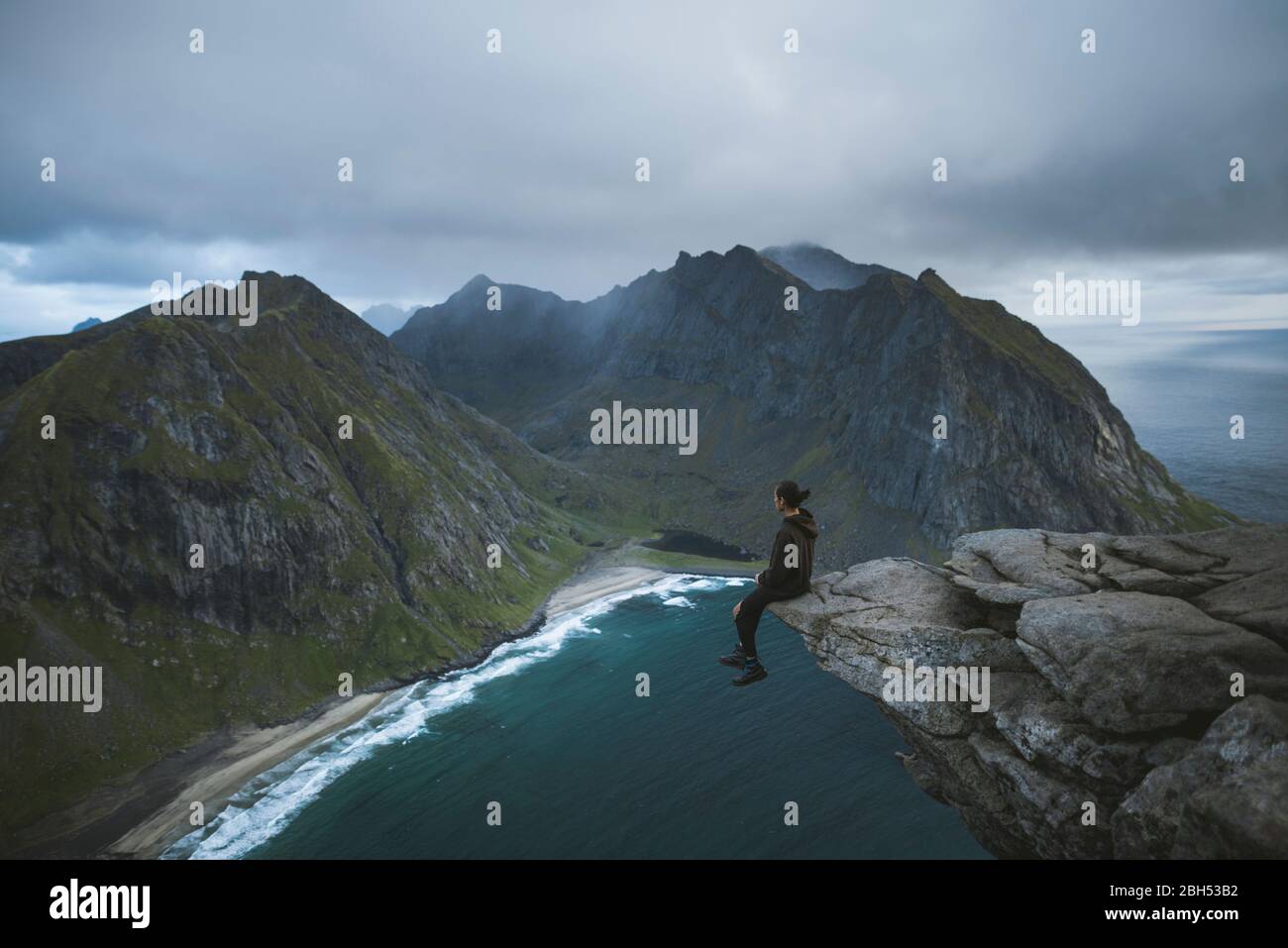 Man sitting on cliff at Ryten mountain in Lofoten Islands, Norway Stock ...