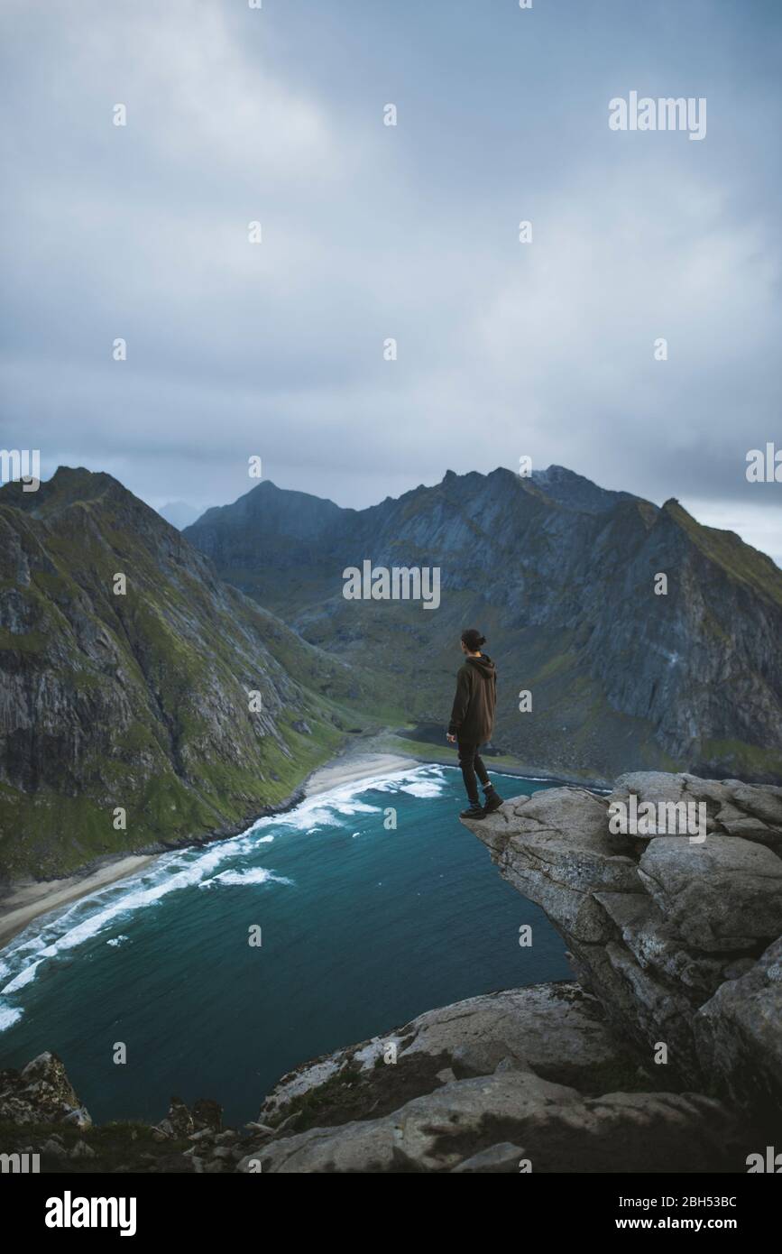 Man standing on cliff at Ryten mountain in Lofoten Islands, Norway ...