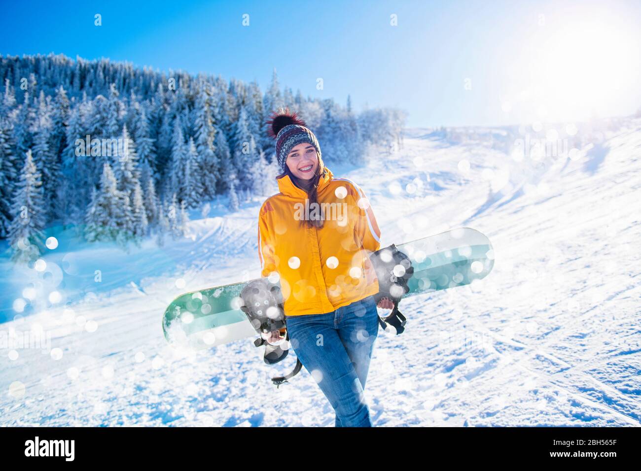 Sporty female holds snowboard in mountains in jeans Stock Photo - Alamy