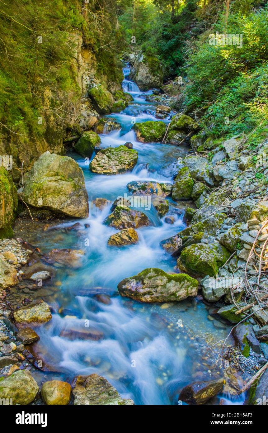 Fresh water from the mountain stream flows pure in the greenery and in ...