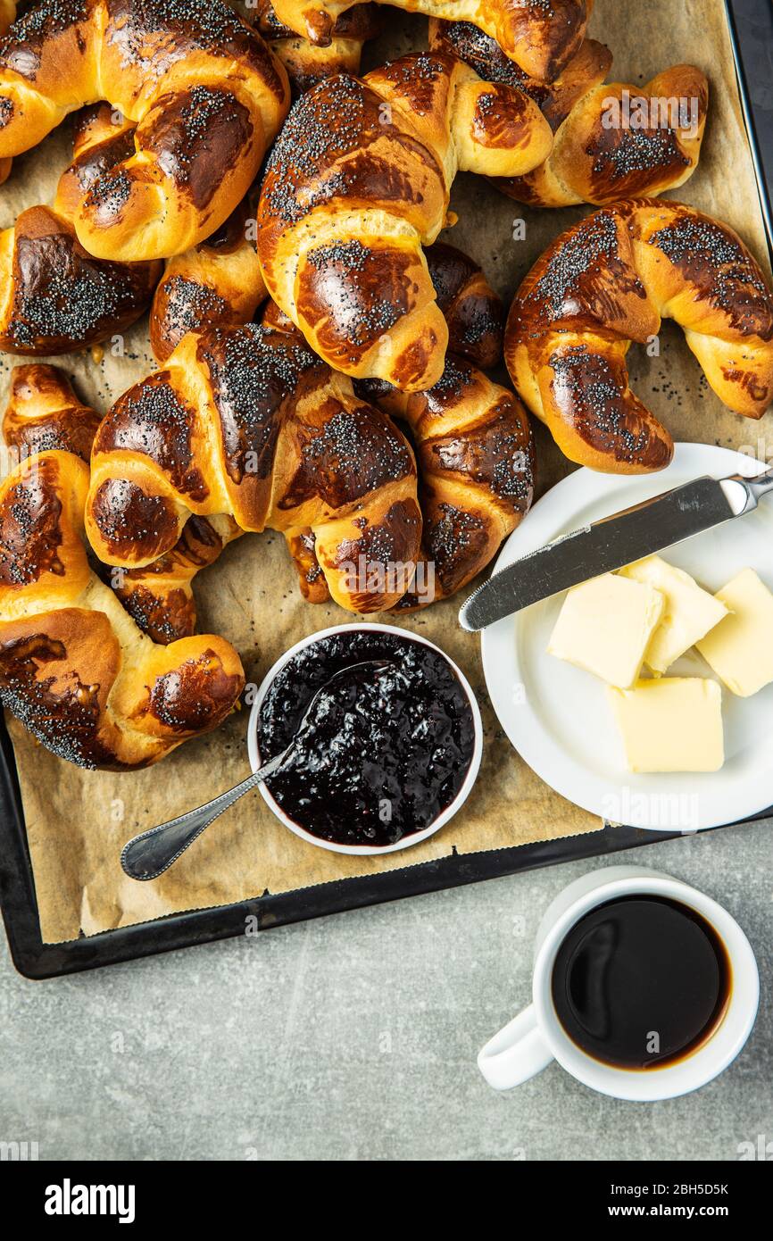 Sweet homemade croissants with poppy, jam, butter and coffee on wooden ...
