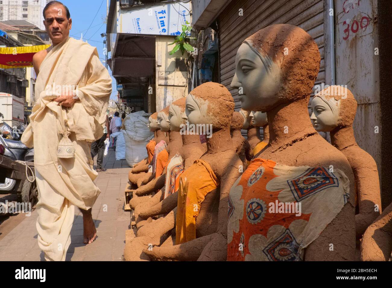 A Jain priest in Mumbai, India, passes newly made clay figures of Hindu ...