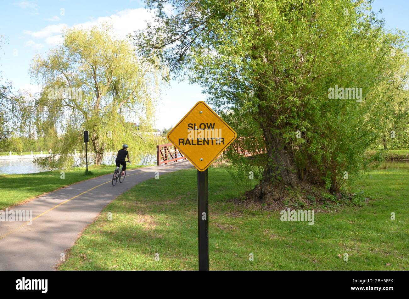 path with biker and slow sign in French and English and grass Stock ...