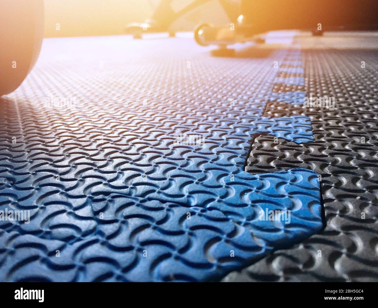 The photo of The blue rubber gym floor with the shadow of dumbell ...