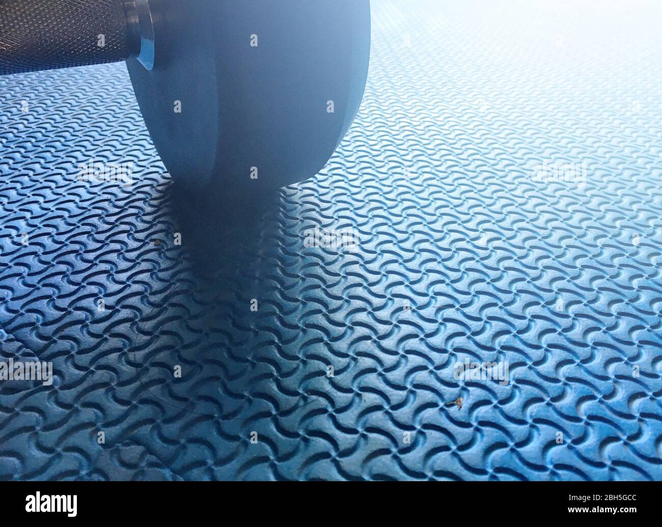 The photo of The blue rubber gym floor with the shadow of dumbell ...