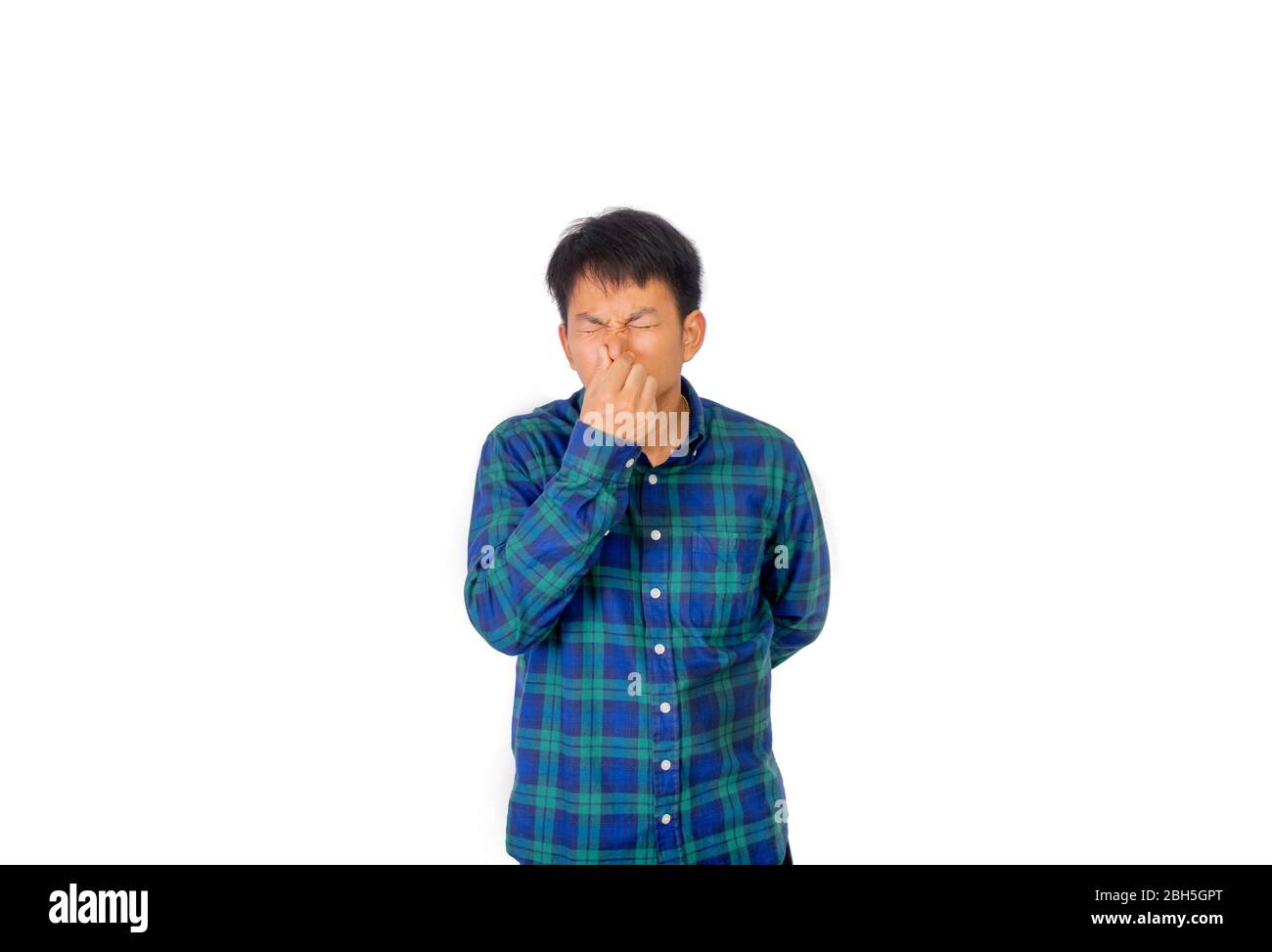 The Asian man in blue plaid shirt is smelling something stinky and ...