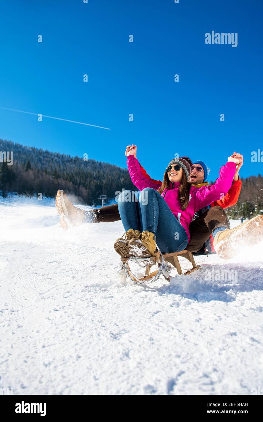 Young happy couple sledding in winter at ski center Stock Photo - Alamy