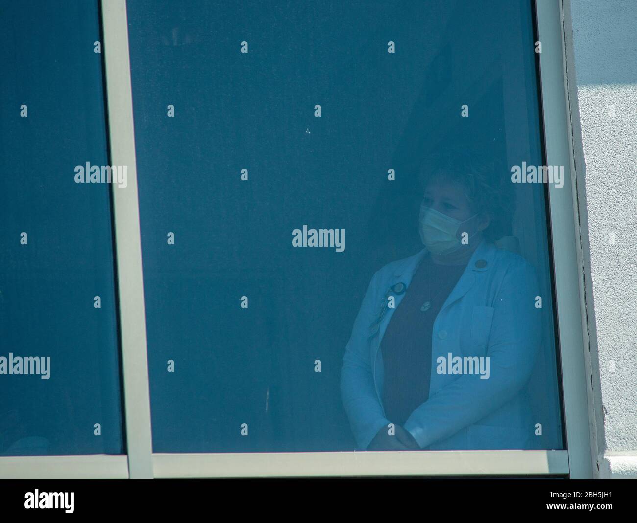 A woman stands in a second floor window watching fire, police and ...