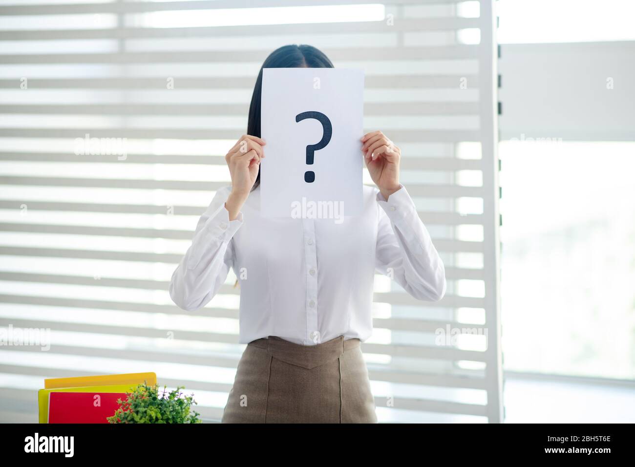 At work. Young female holding sign with question mark Stock Photo - Alamy