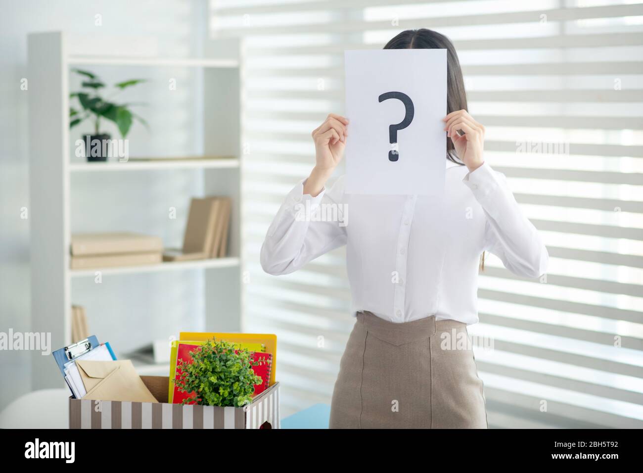 At work. Young female holding sign with question mark Stock Photo - Alamy