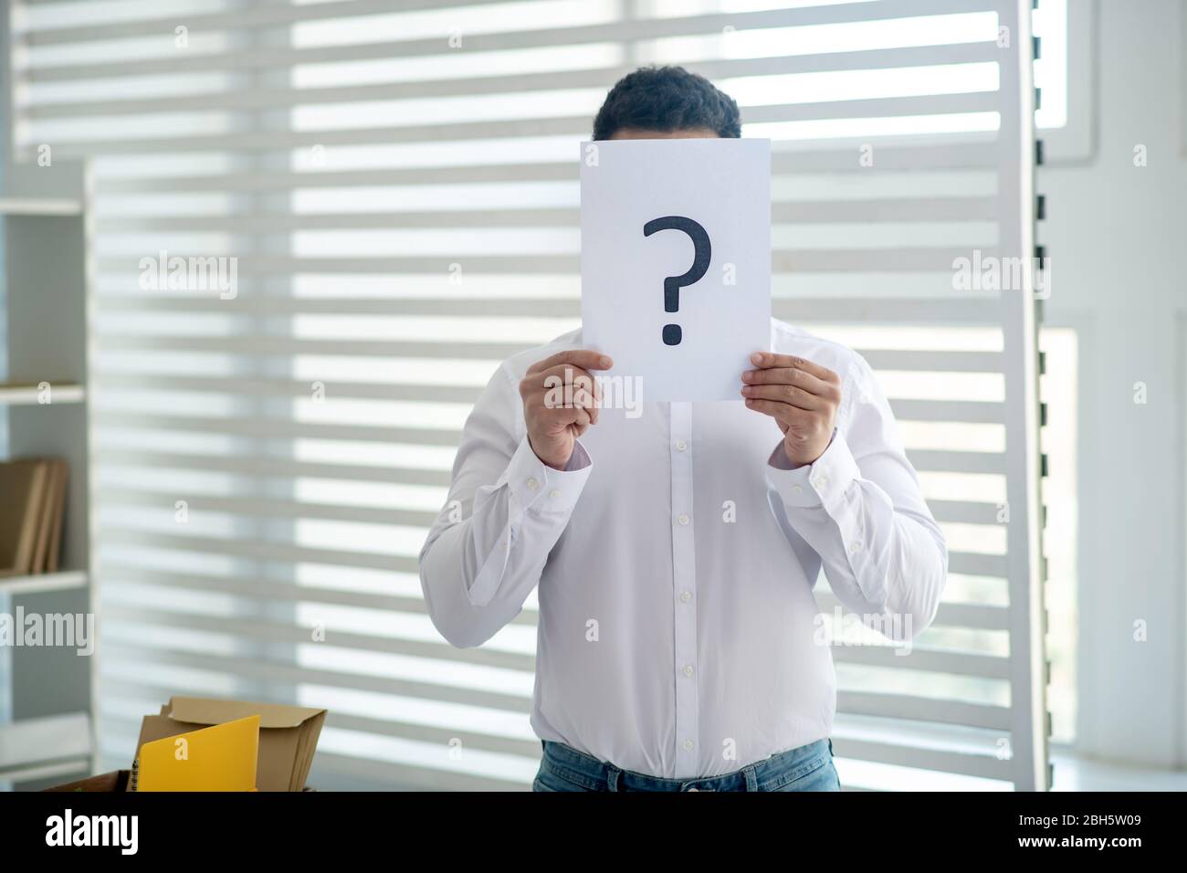 At work. Young male holding sign with question mark Stock Photo - Alamy