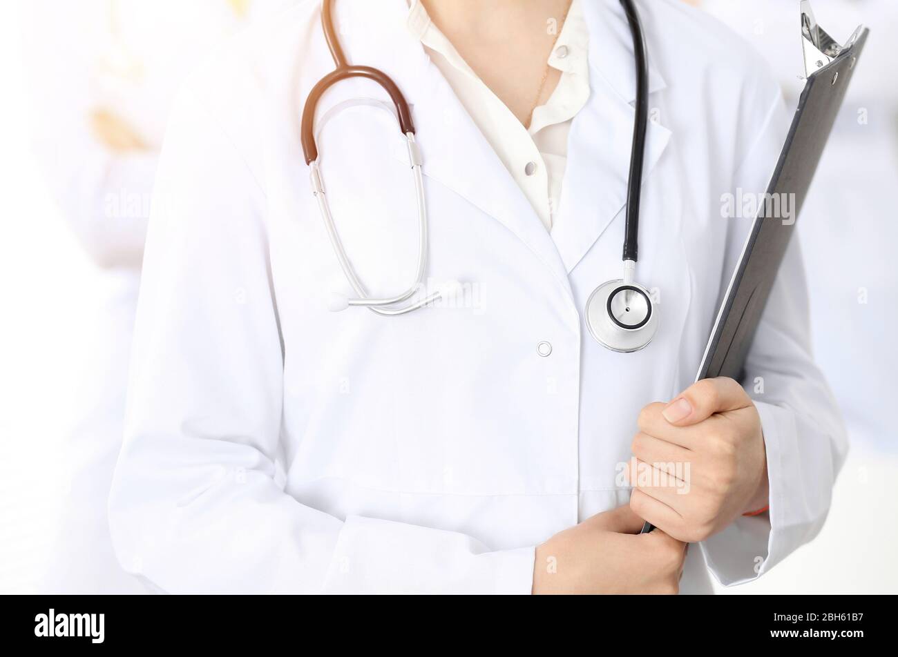 Unknown woman-doctor standing straight with clipboard of medication ...
