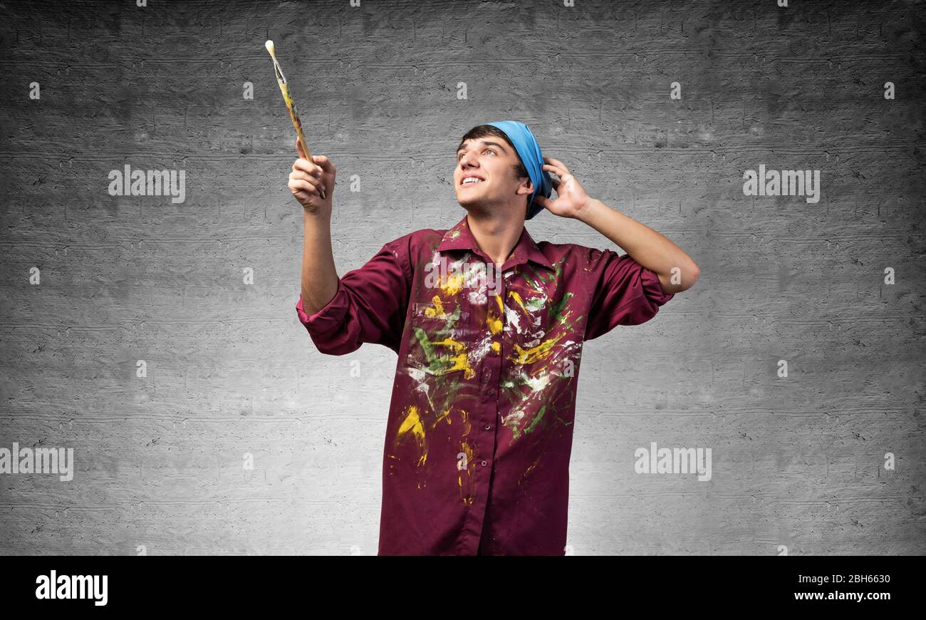 Smiling young painter artist pointing upwards Stock Photo - Alamy