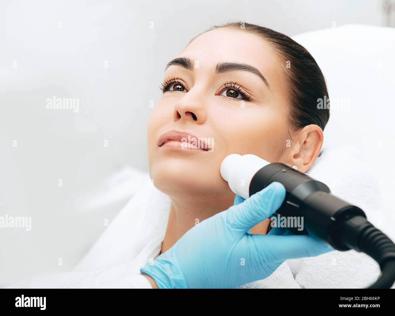 doctor doing an acoustic wave therapy to a woman. Skin rejuvenation ...