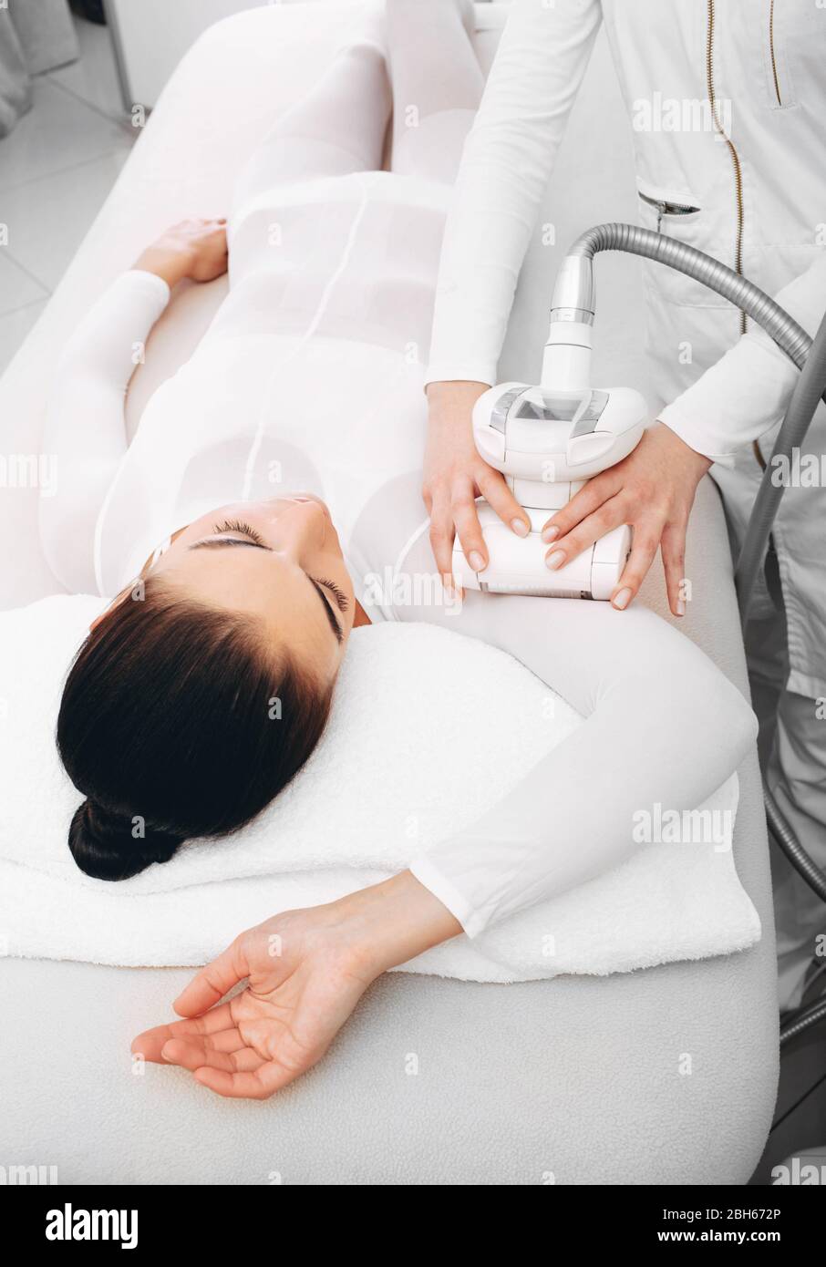woman lying comfortably in a massage table during the LPG massage procedure. Beautician removes ...