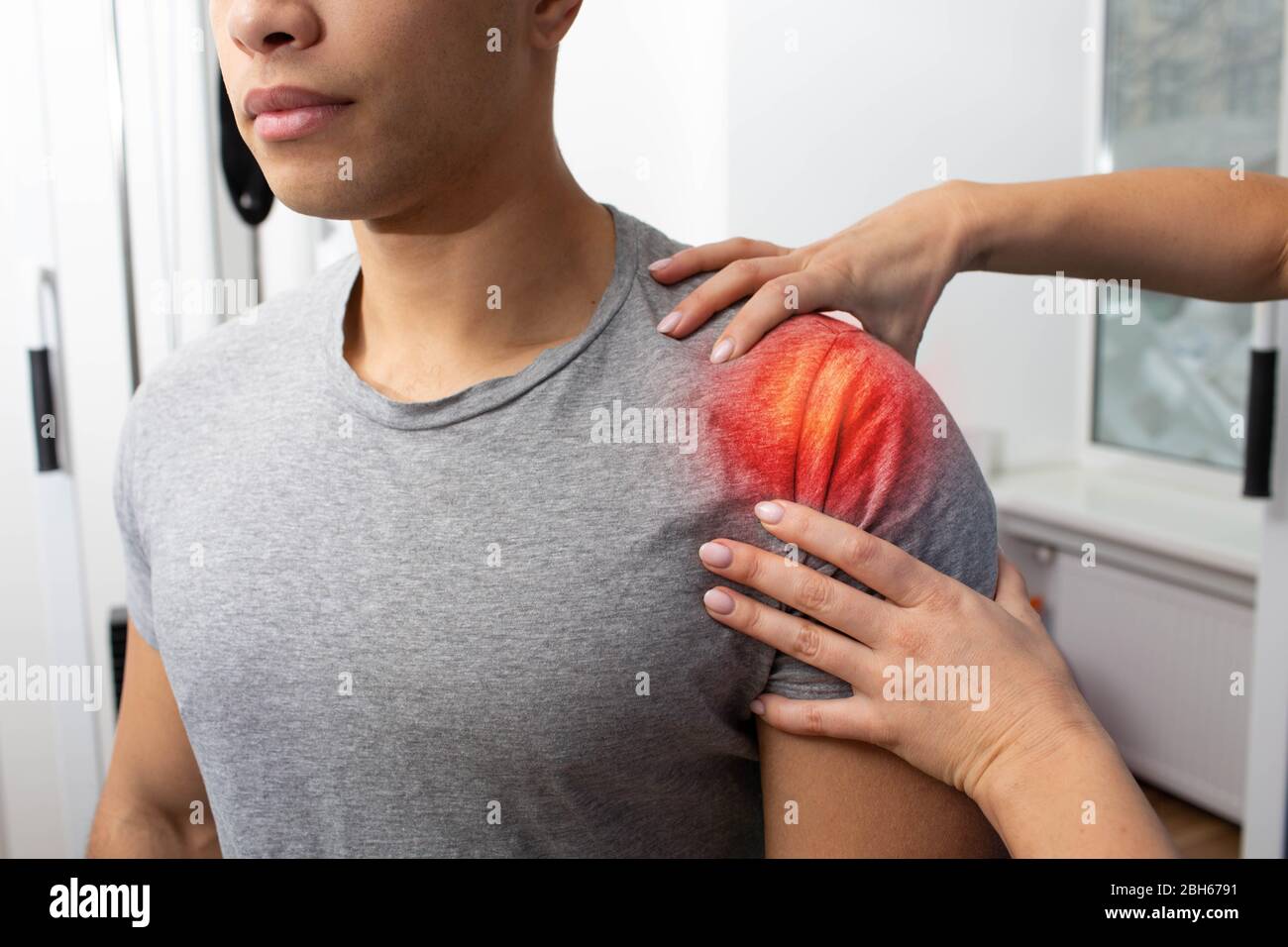 Athlete suffers from shoulder pain. Physiotherapist helps treat ...
