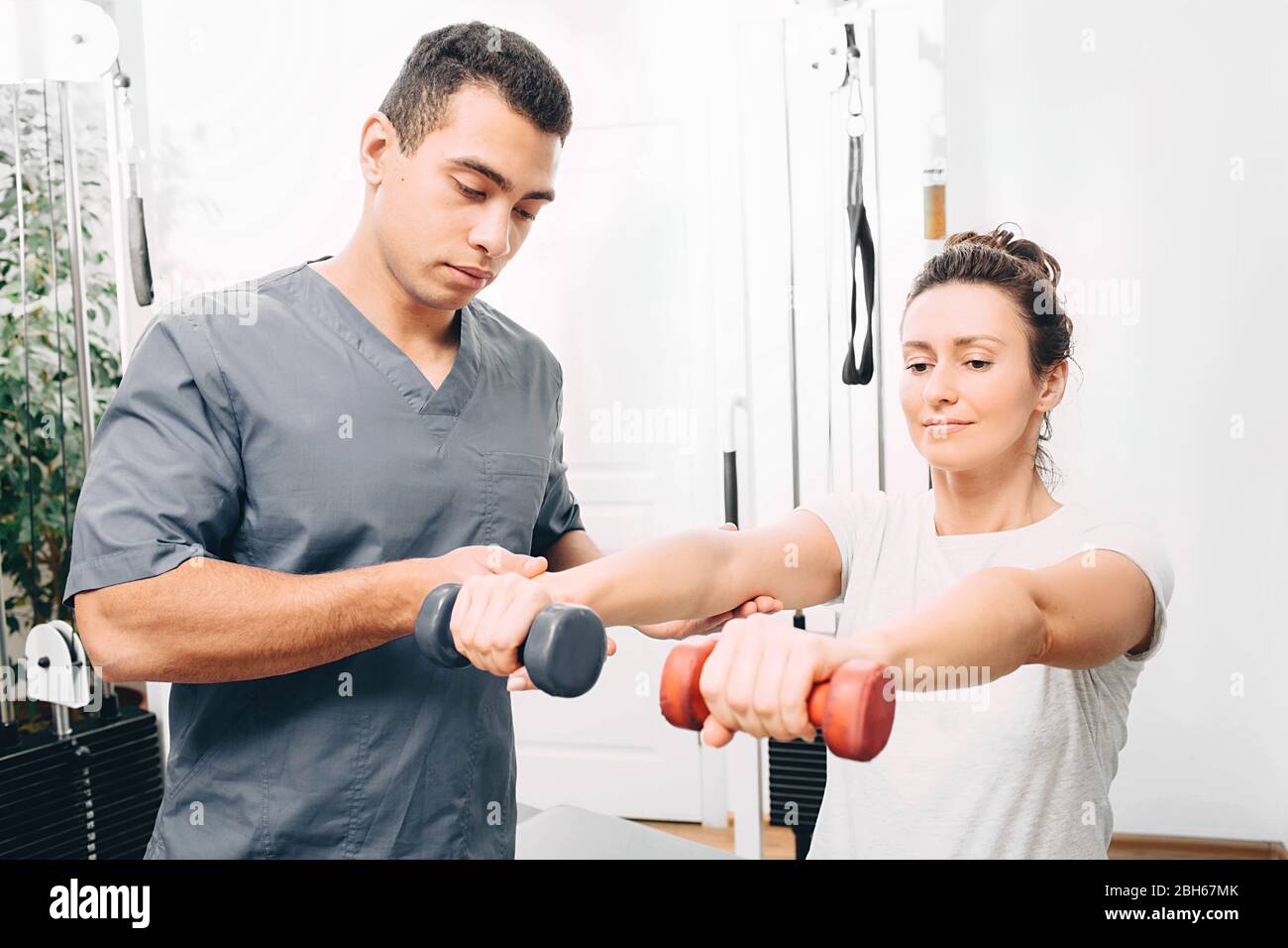 Physiotherapist helps a woman do physical exercises to treat ...