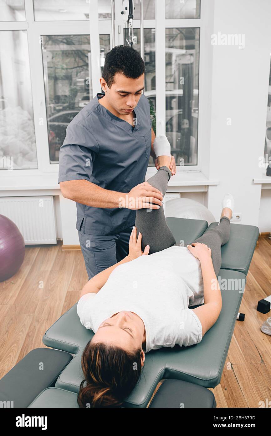 woman during exercises with her physiotherapist treating back and joint ...