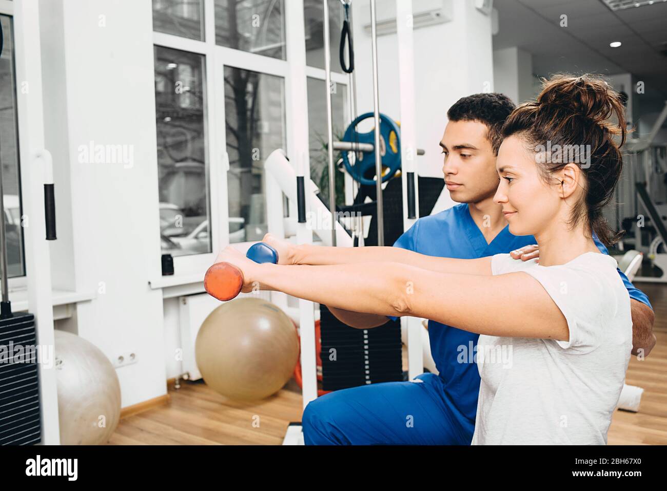 Physiotherapist helps a woman do physical exercises to treat ...