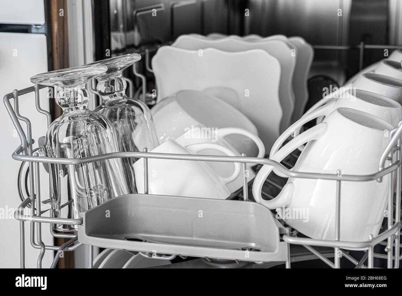 In the basket of the dishwasher is a lot of clean dishes. Cups and ...