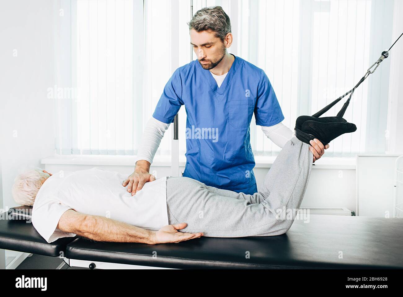 kinesiologist doing therapeutic exercises for an elderly patient ...