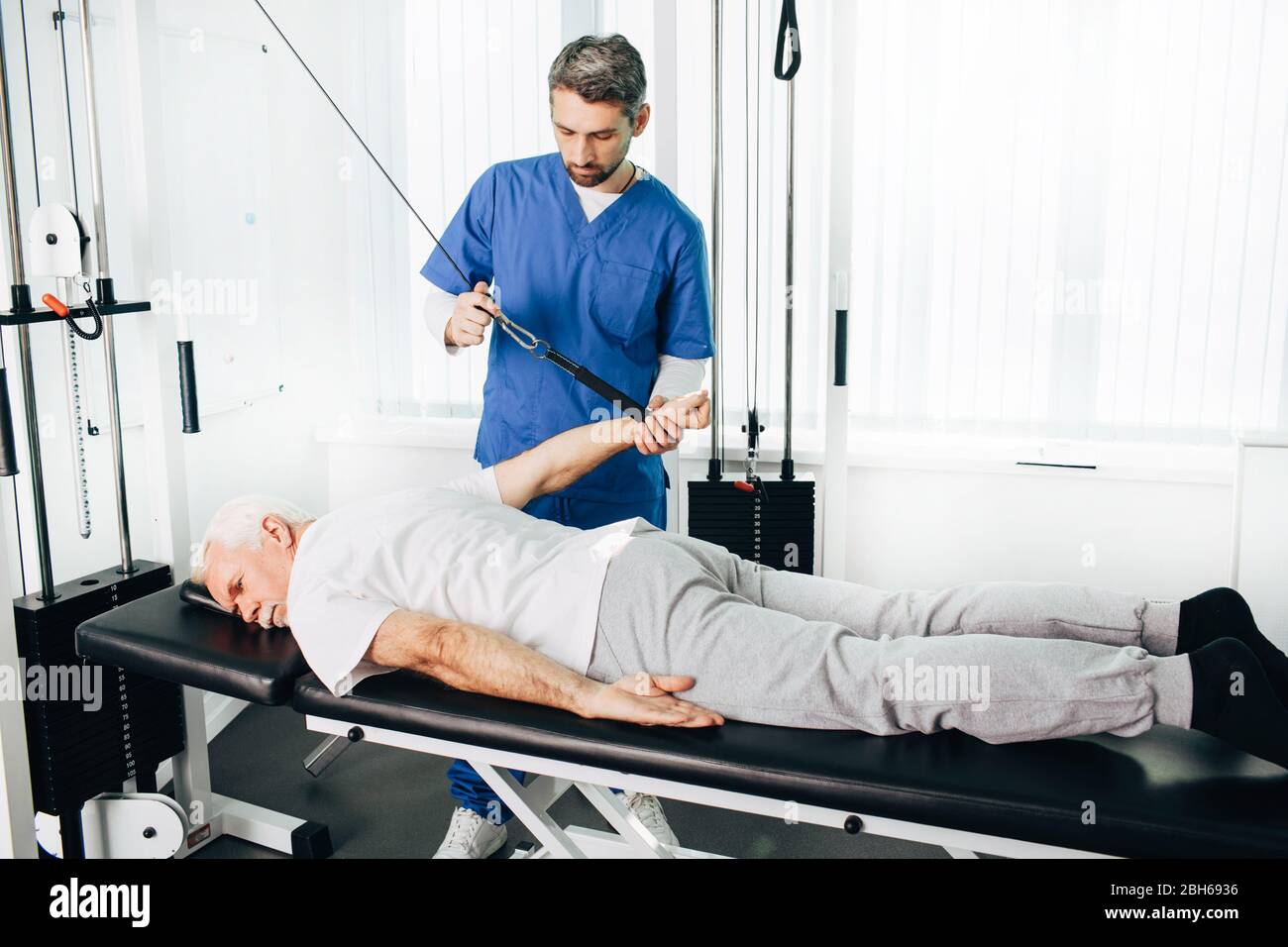 kinesiologist doing therapeutic exercises for an elderly patient ...