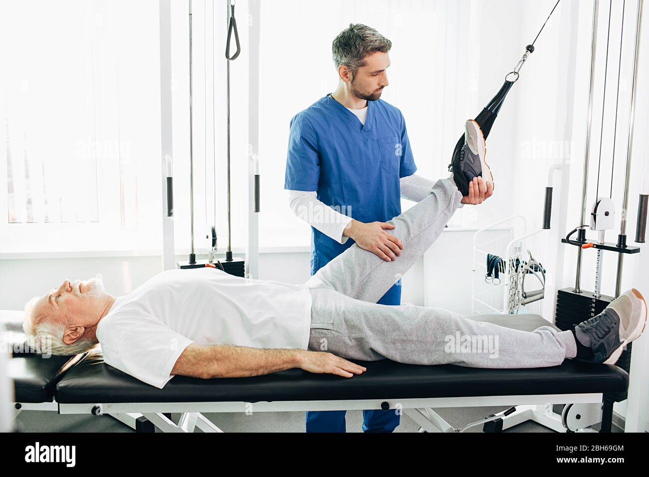 male kinesiotherapist assisting a senior patient in recovery with ...