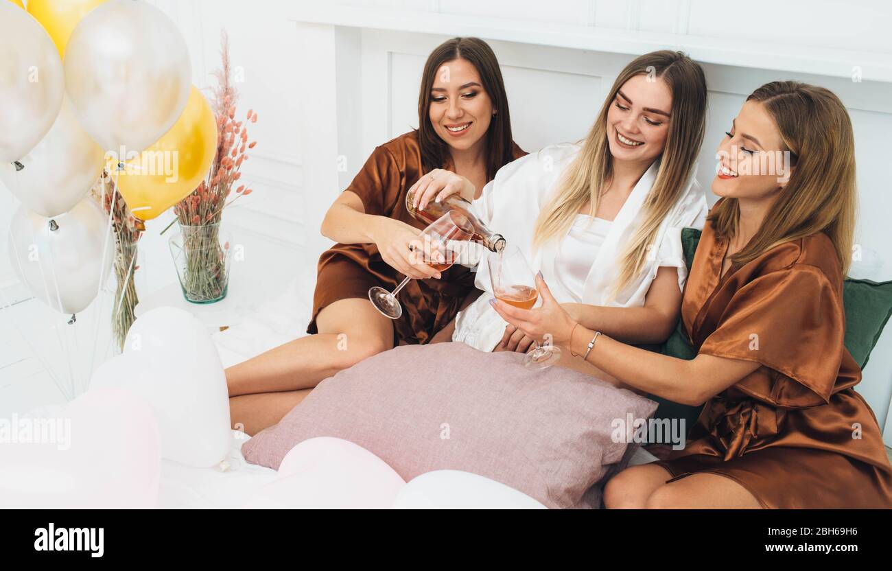 girlfriends with wine enjoying pajamas party at home. Celebrating hen ...