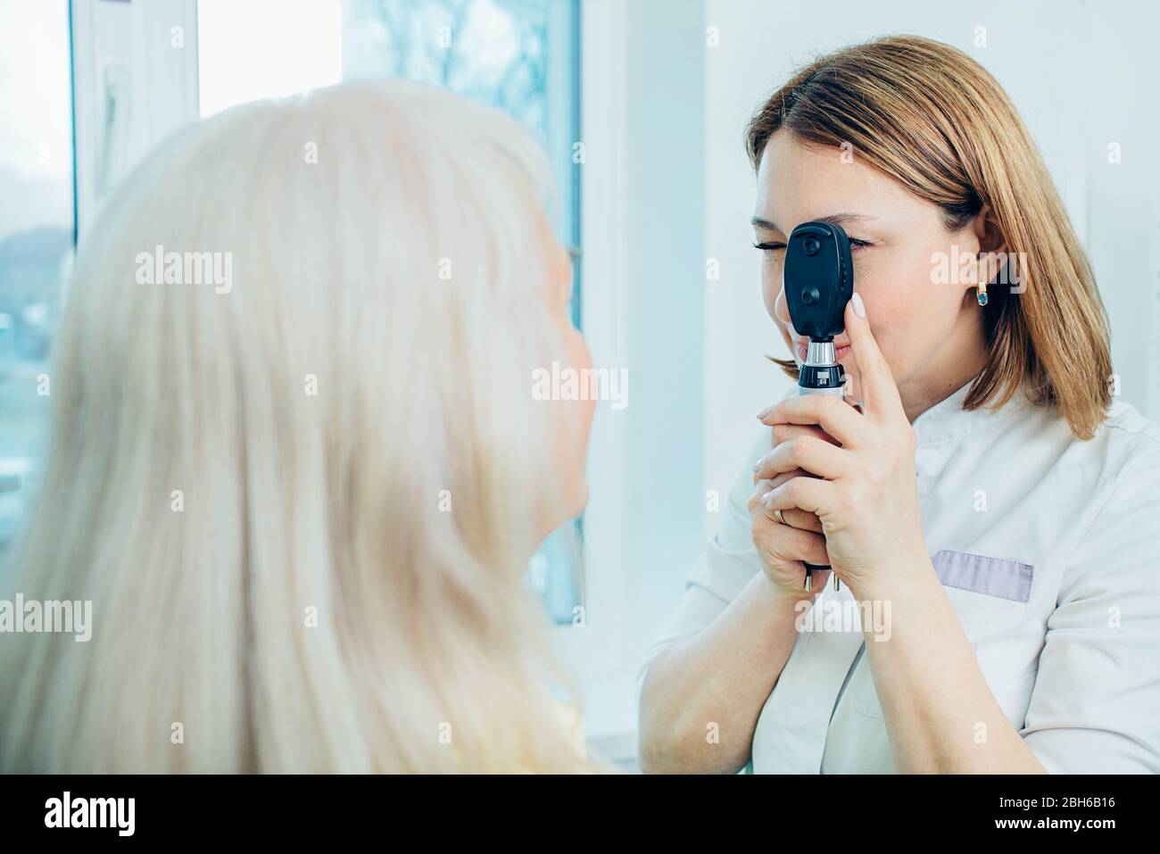 doctor Optometrist examining old man's eyes with special eye equipment ...