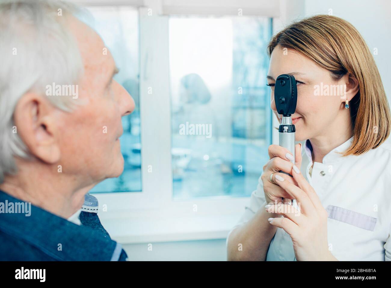 Doctor Optometrist examining old man's eyes with special eye equipment ...