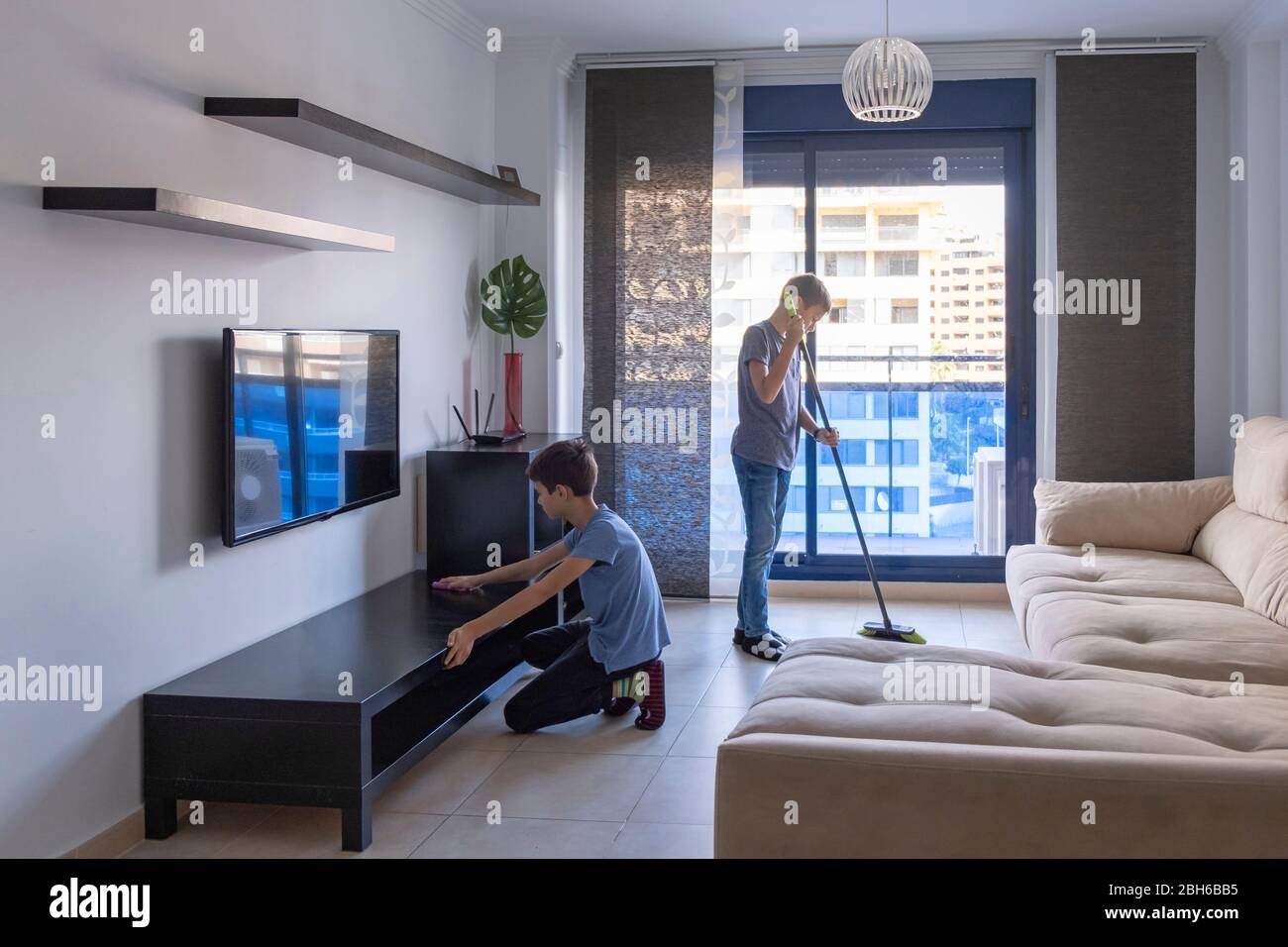 Children sweeping floor and cleaning dust in living room at home ...