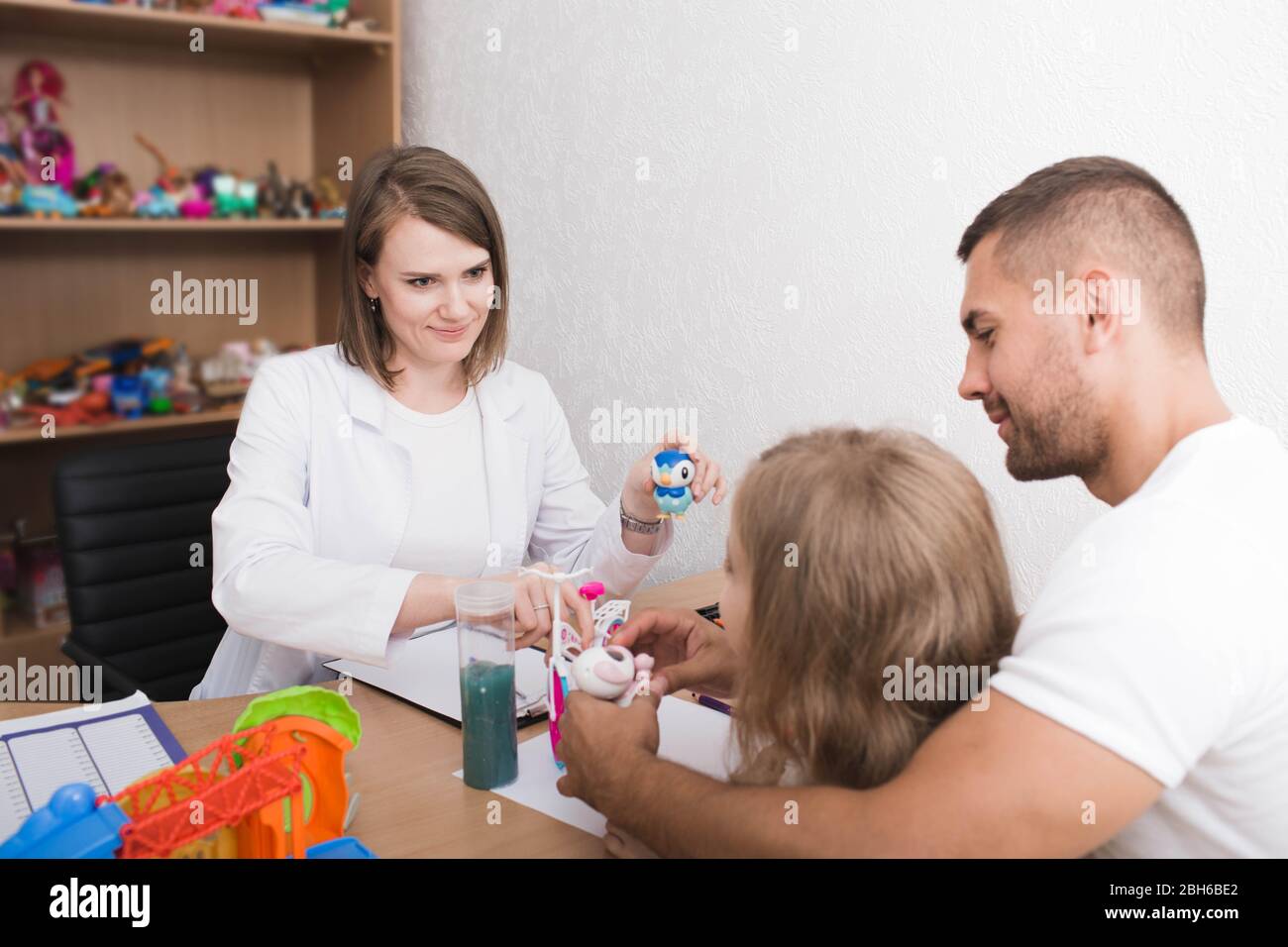 Child psychologist talks with a child and father in the office of a ...