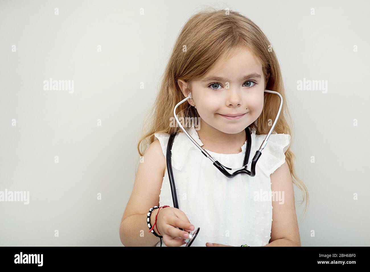 Cute little girl holding otoscope standing on gray background Stock ...