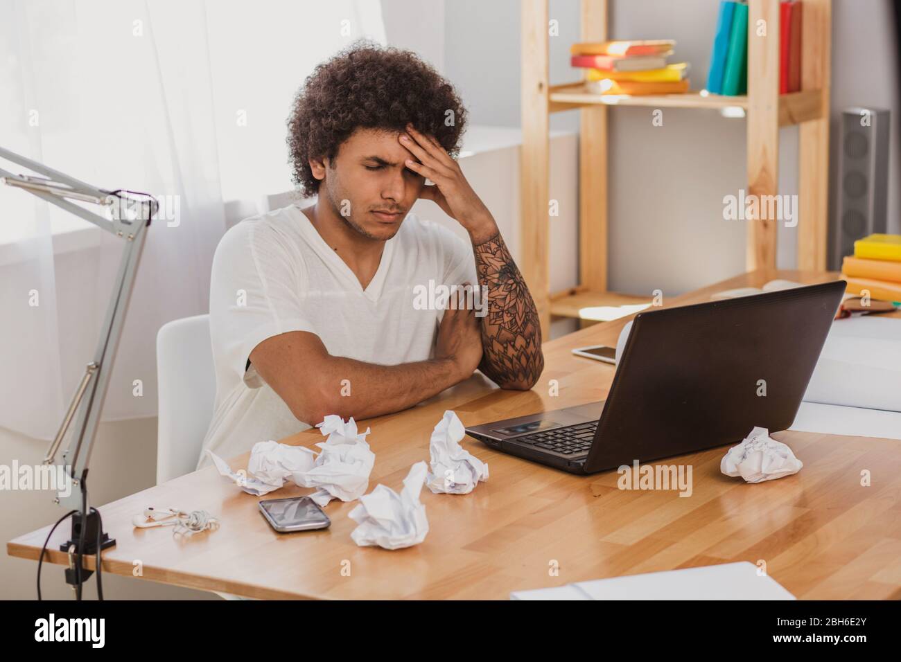 Attractive dark man designer, feeling tired, leaning his head on hand ...