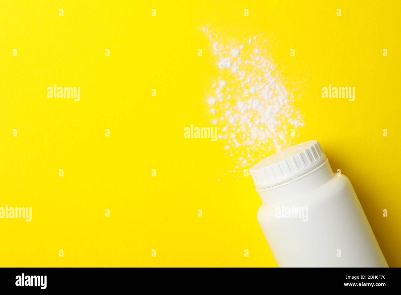 Blank bottle of talcum powder on yellow background, space for text ...