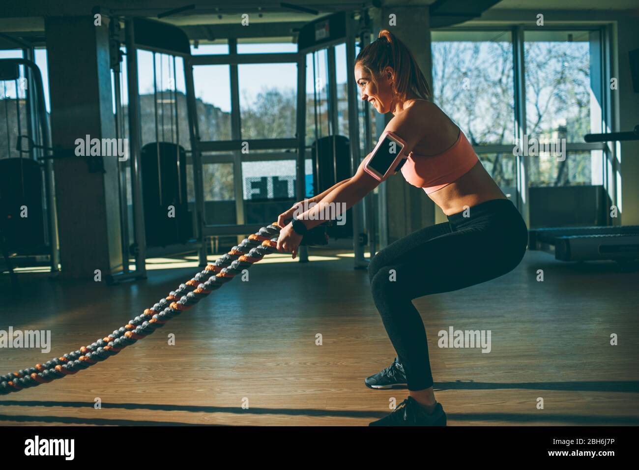 Pretty young woman with battle ropes exercise in the fitness gym Stock ...