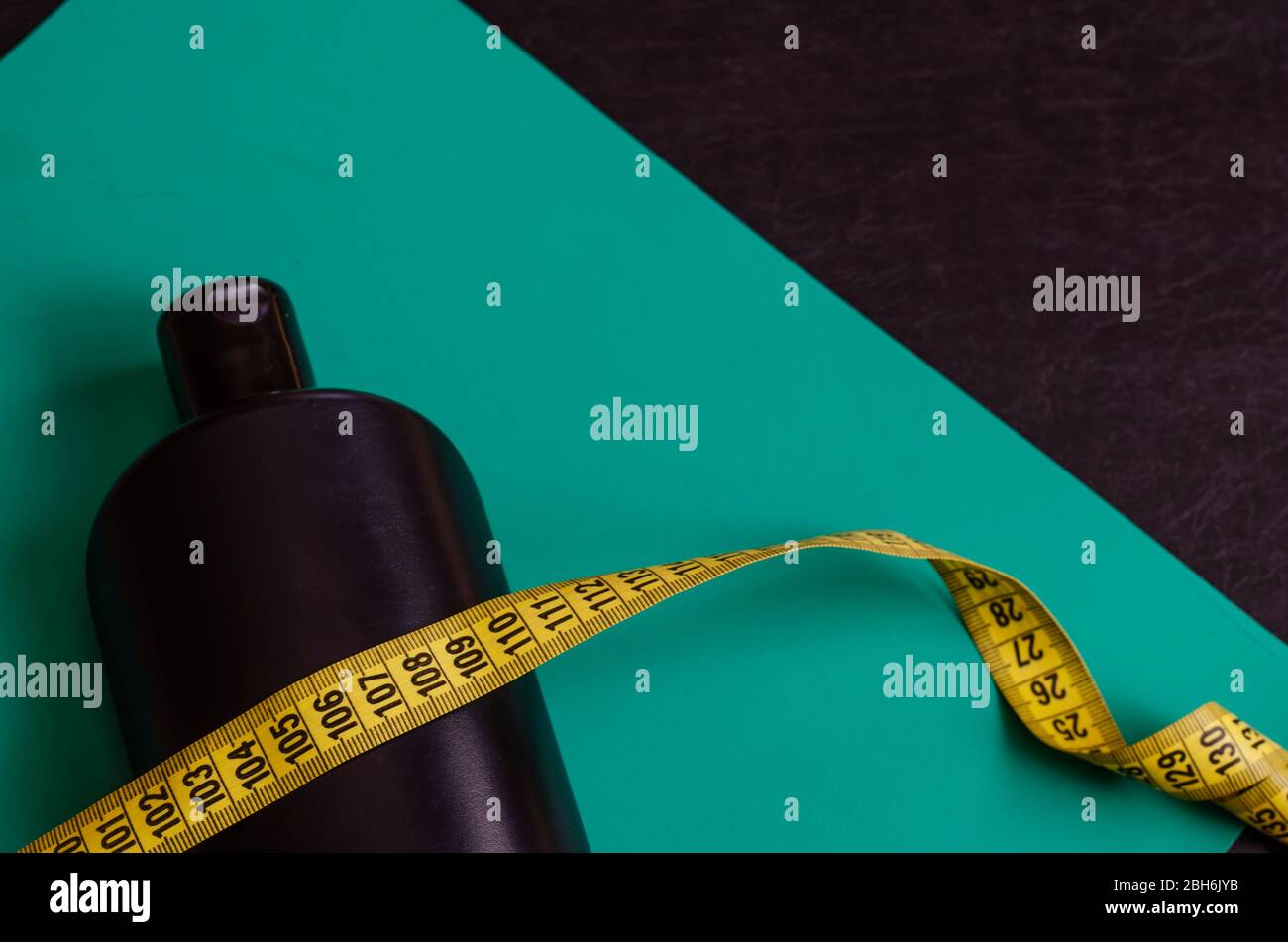 Black plastic bottle and tailor meter on a turquoise background. Black ...