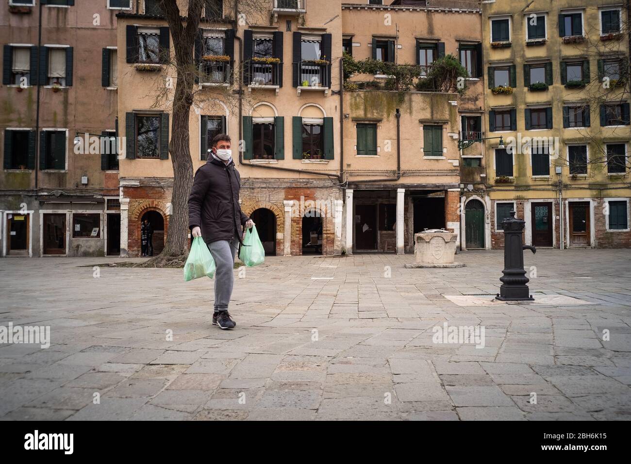 VENICE, ITALY - APRIL 2020: A man with protective mask walk in an empty ...
